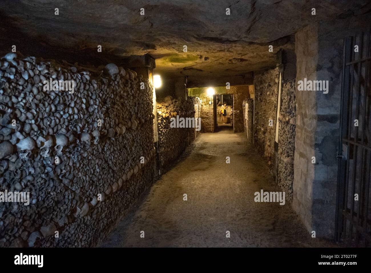 In the Paris Catacombs, a long underground path with structures formed ...