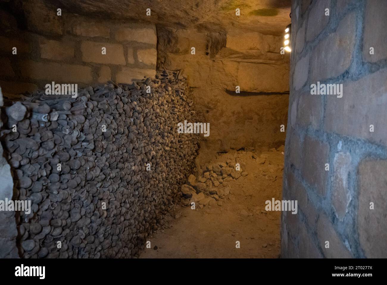 In the Paris Catacombs, a long underground path with structures formed ...