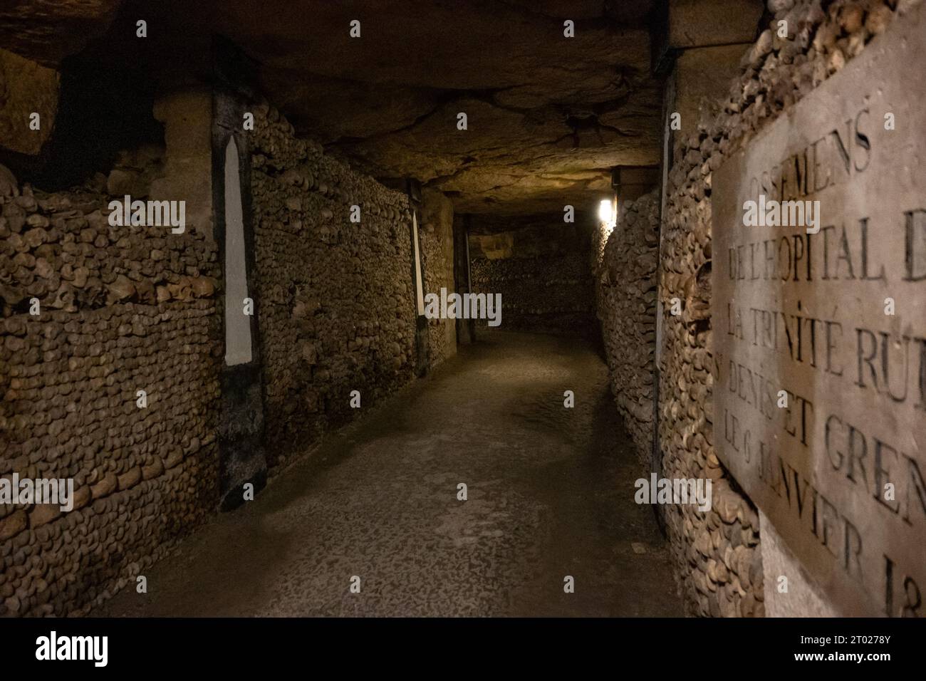 In the Paris Catacombs, a long underground path with structures formed ...