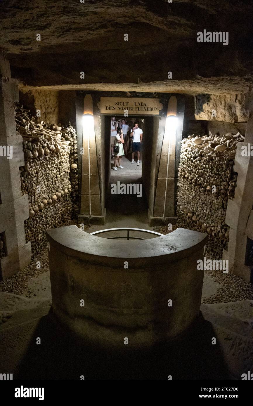 In the Paris Catacombs, a long underground path with structures formed ...