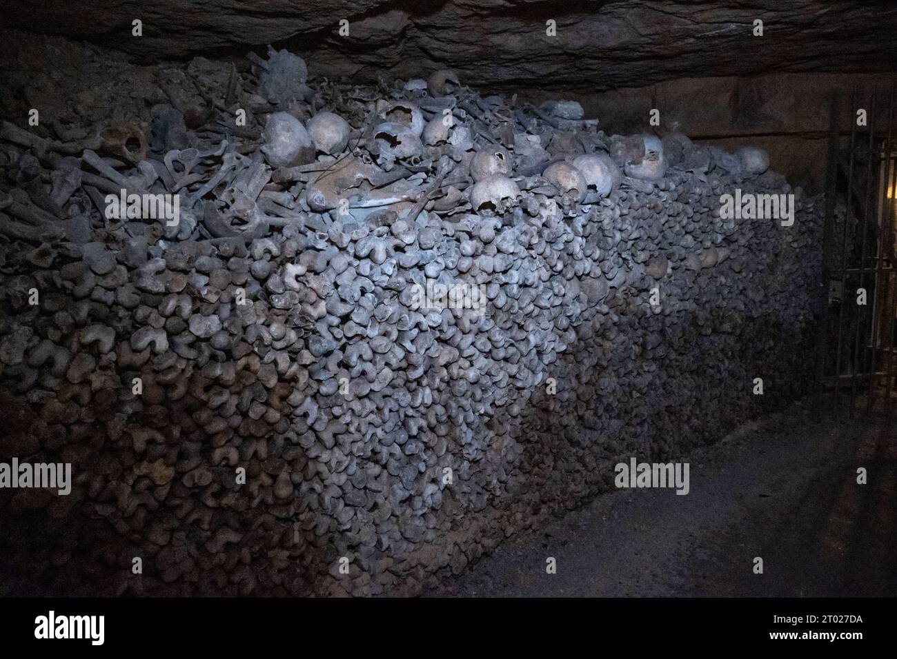 In the Paris Catacombs, a long underground path with structures formed ...