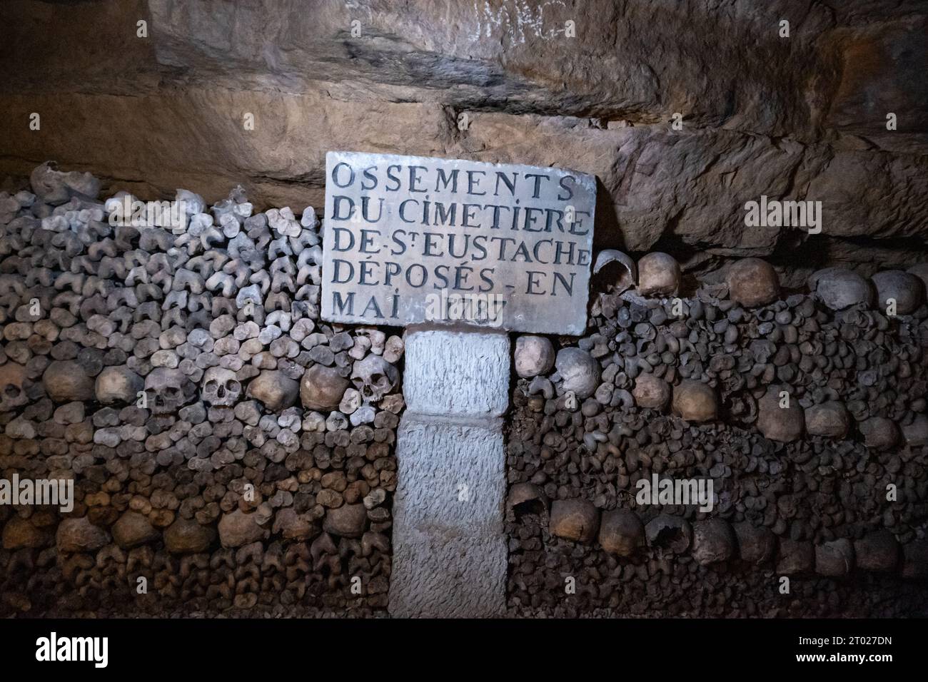 In the Paris Catacombs, a long underground path with structures formed ...