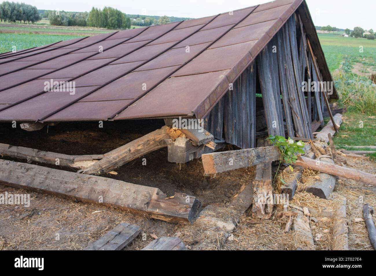 The remains of an old, destroyed metal roof lie on the ground after the ...