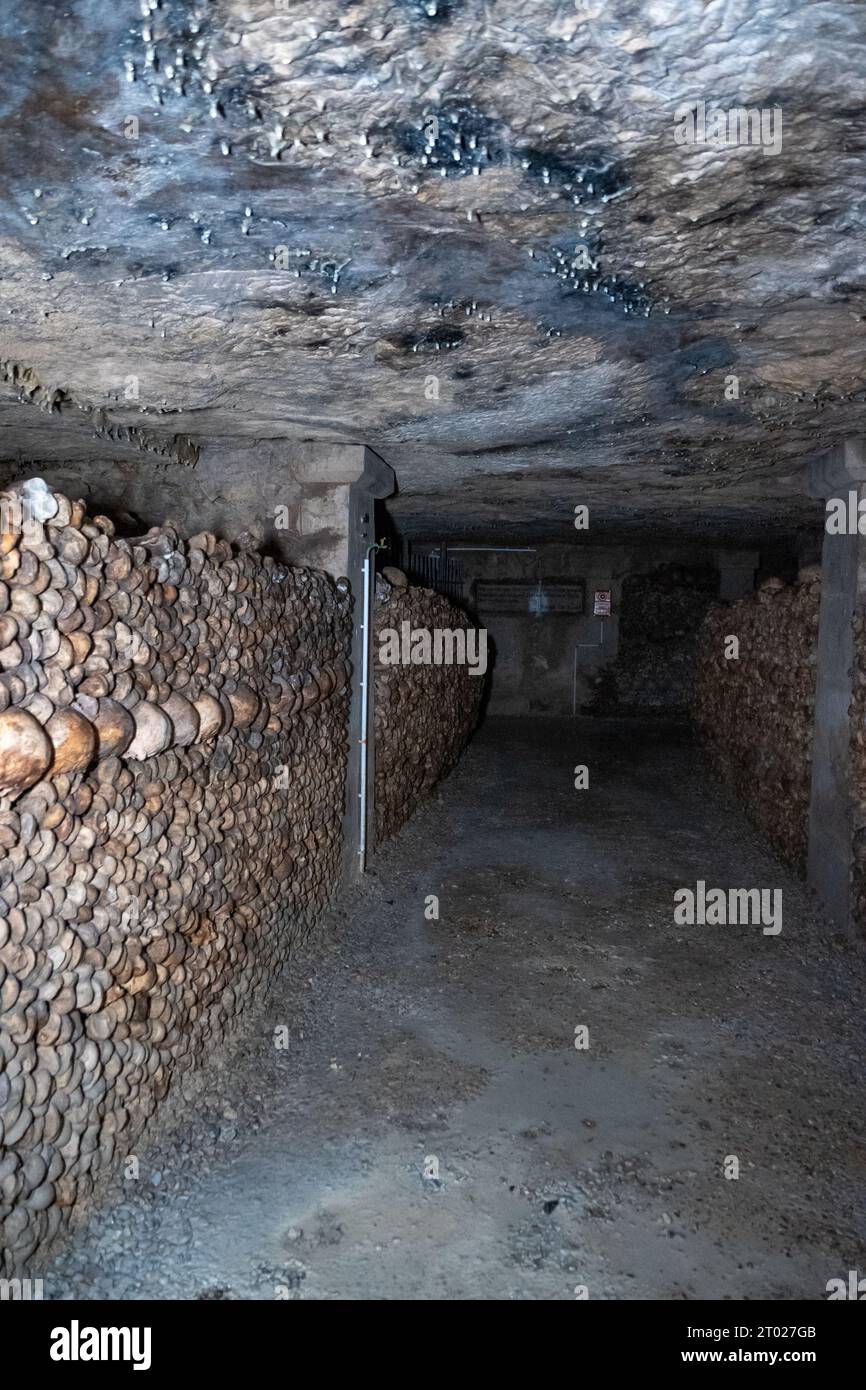 In the Paris Catacombs, a long underground path with structures formed ...
