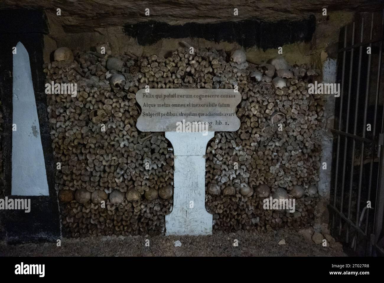 In the Paris Catacombs, a long underground path with structures formed ...
