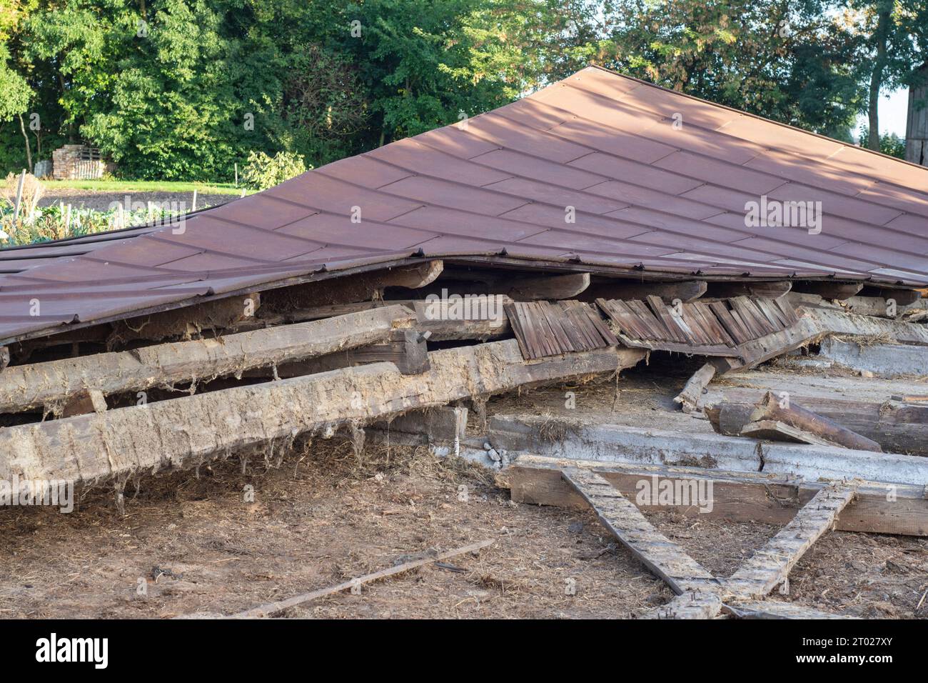 The remains of an old, destroyed metal roof lie on the ground after the ...