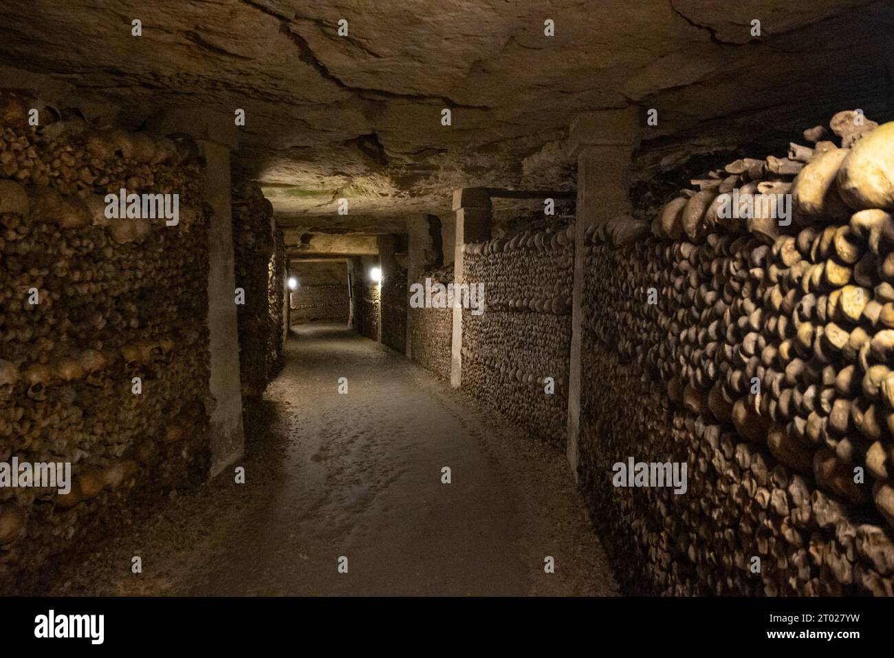 In the Paris Catacombs, a long underground path with structures formed ...