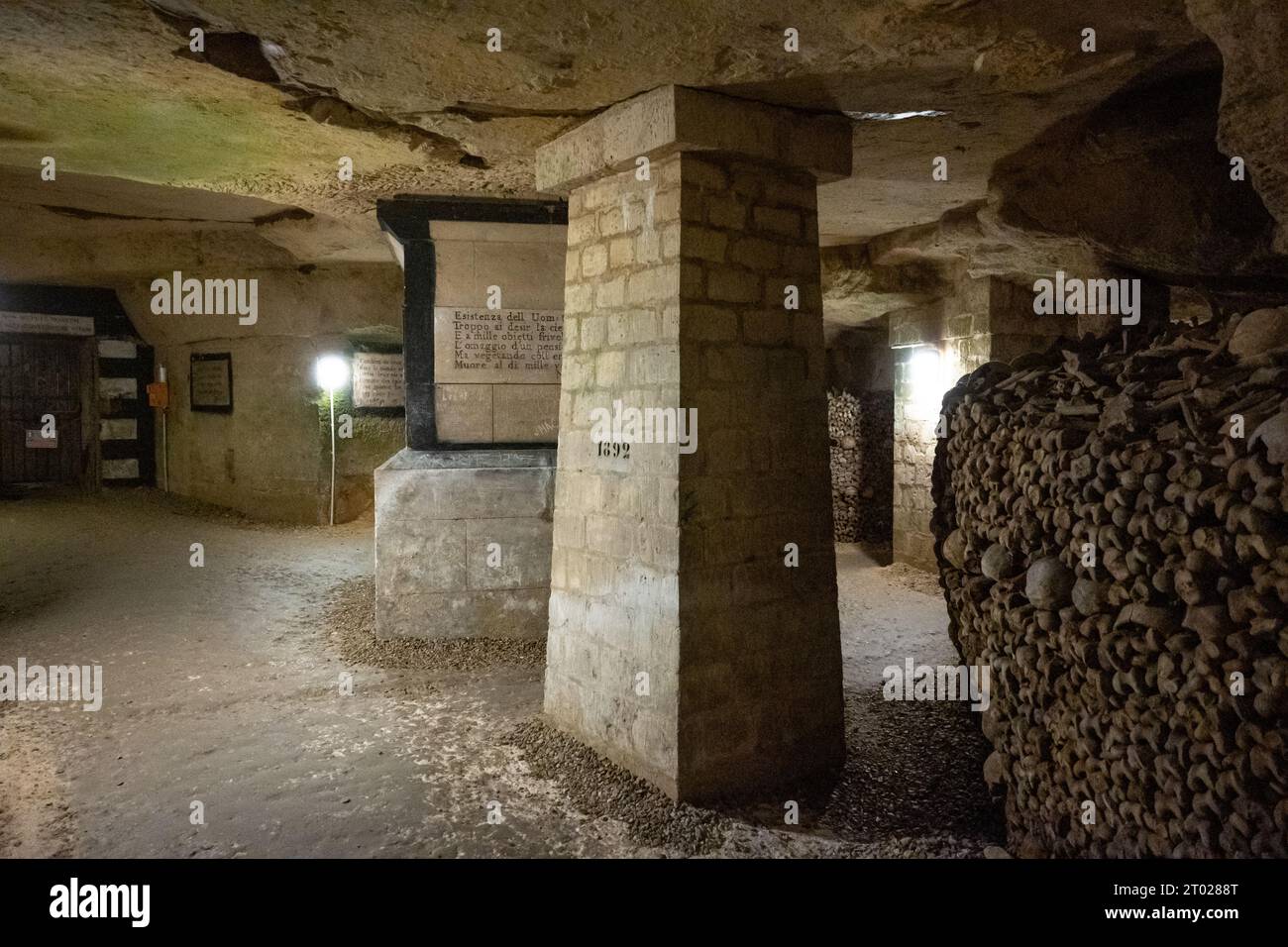 In the Paris Catacombs, a long underground path with structures formed ...