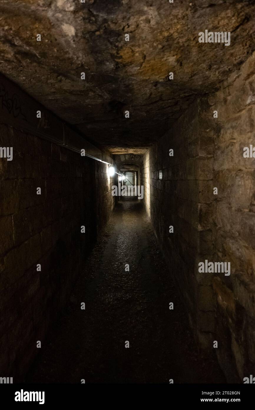 In the Paris Catacombs, a long underground path with structures formed ...