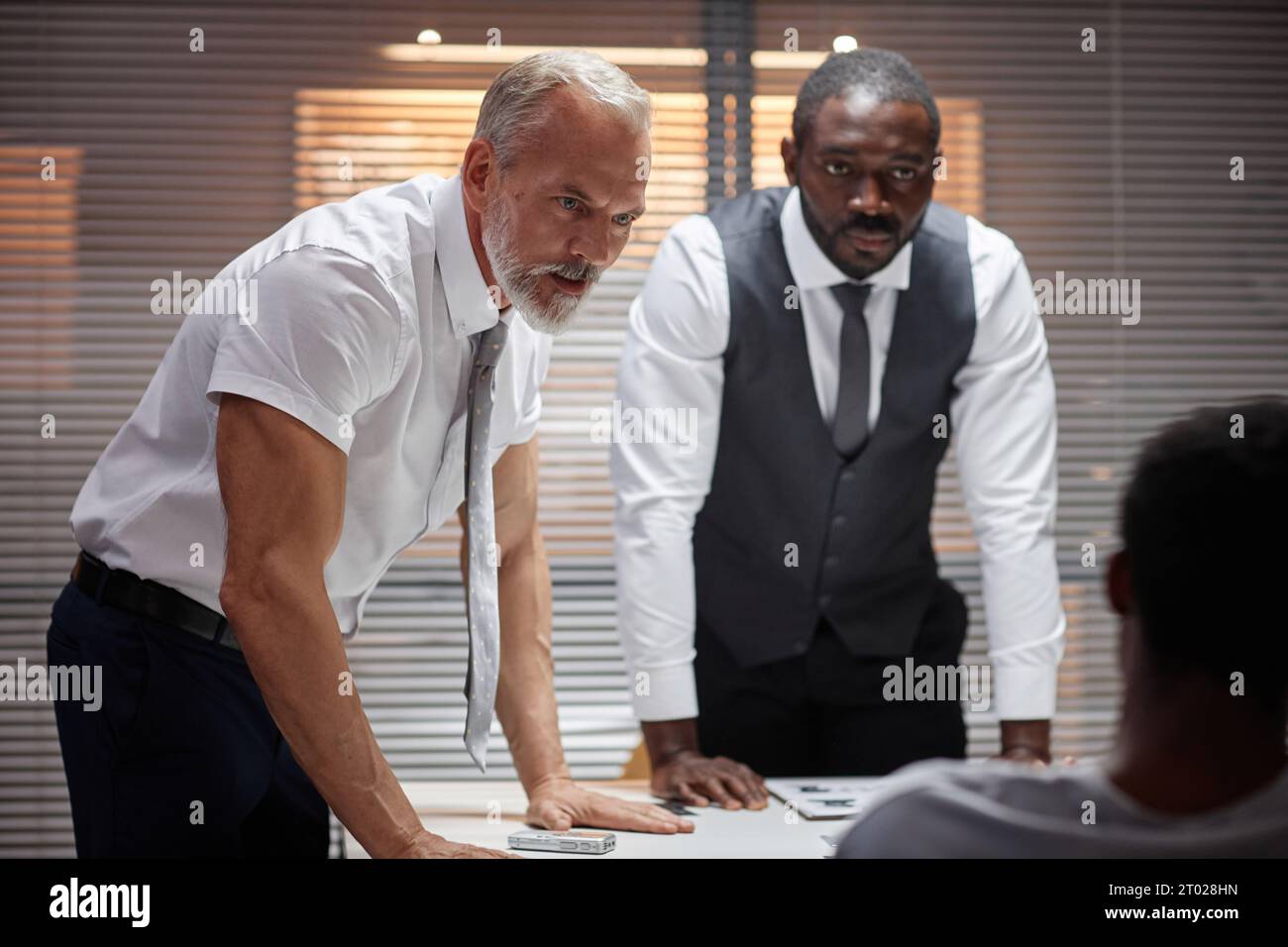 Portrait of handsome mature detective interrogating suspect in police ...