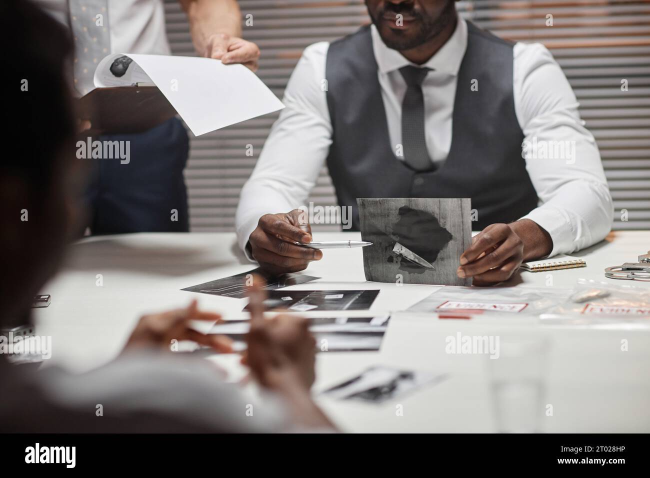Close up of male detective holding pictures with evidence during ...