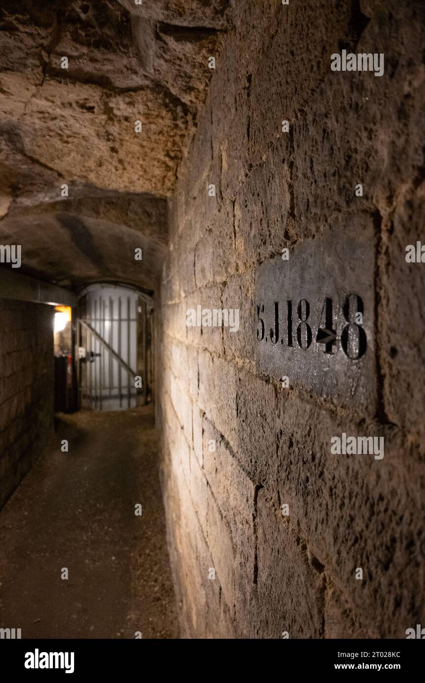 In the Paris Catacombs, a long underground path with structures formed ...