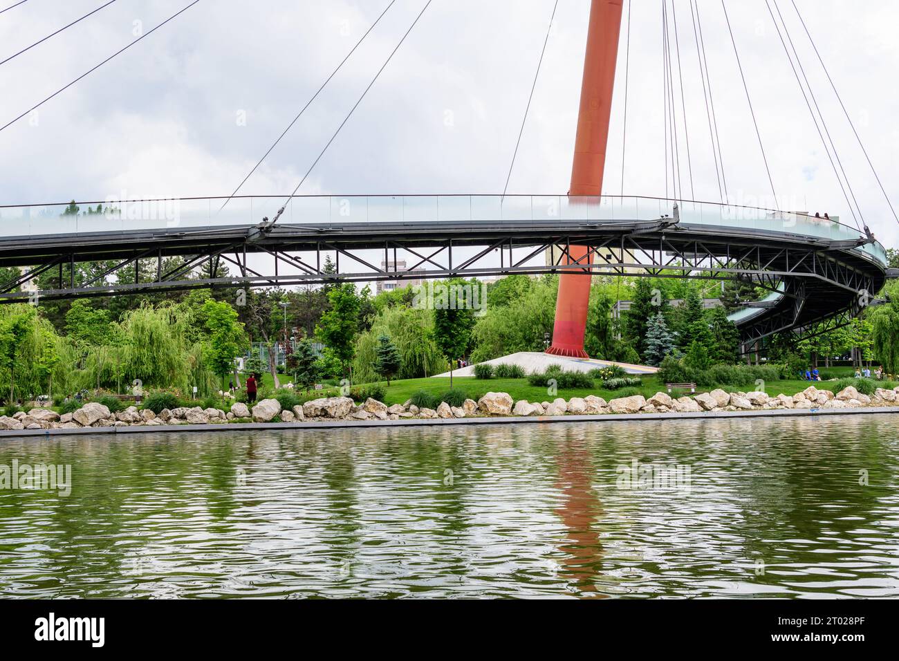 Landscape with the modern red metallic bridge, lake and vivid green ...