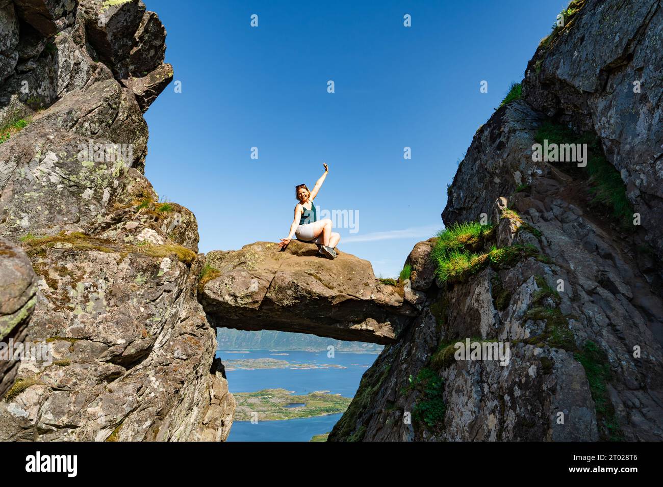 Brave traveler woman standing on hanging stone between rocks ...