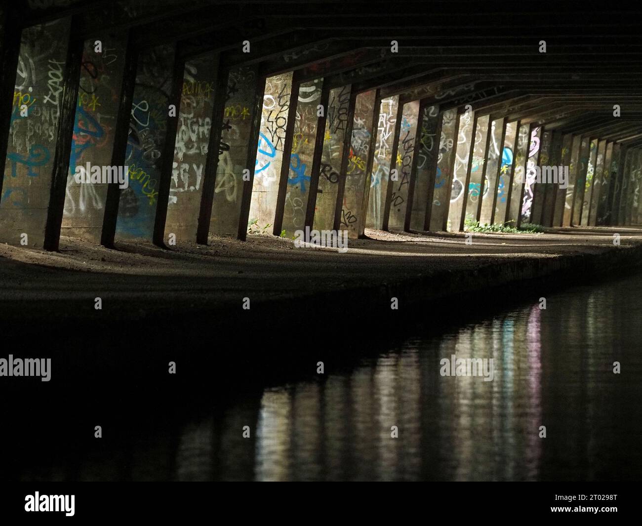 colourful graffiti on concrete arches of modern bridge over inland ...