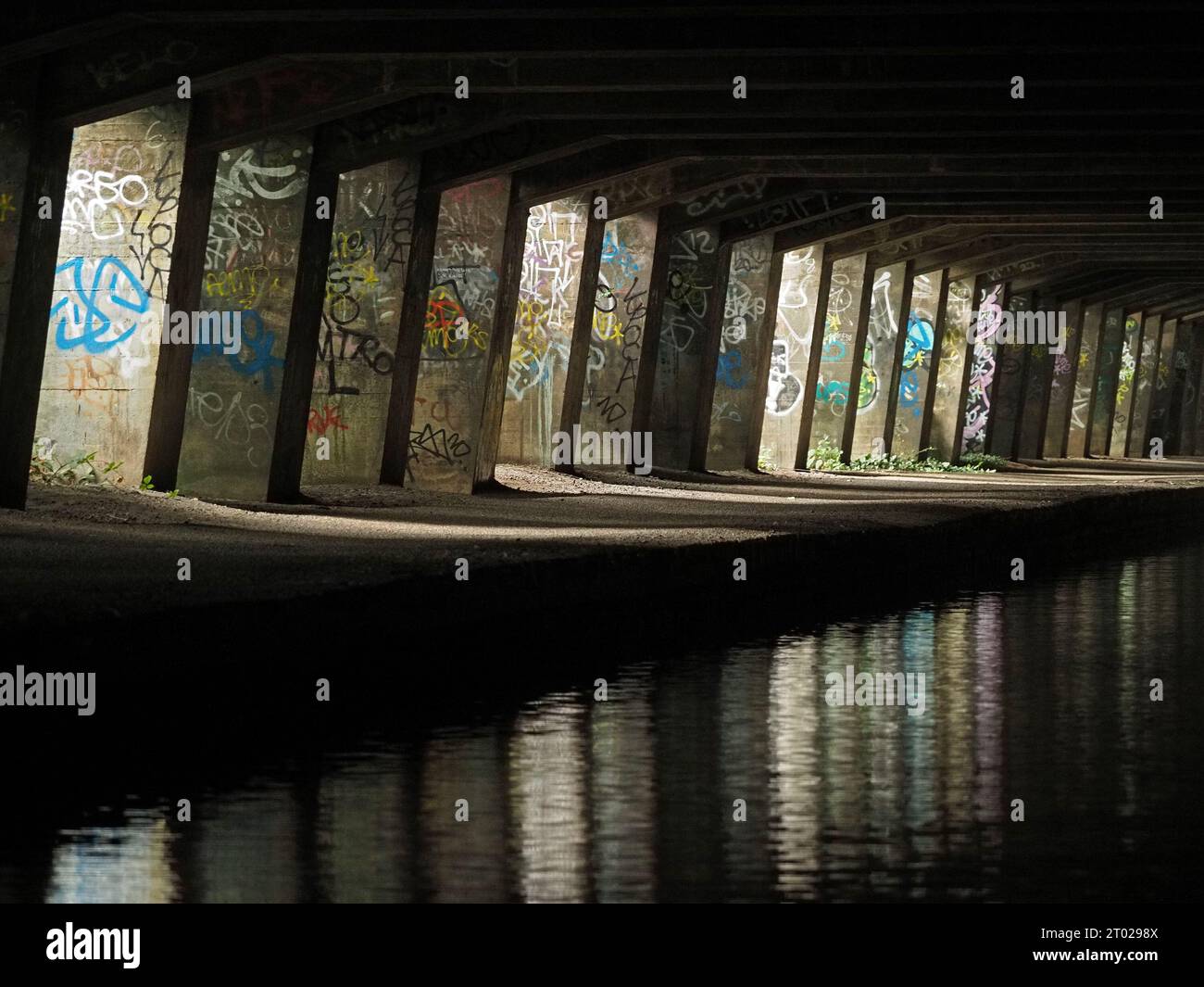 colourful graffiti on concrete arches of modern bridge over inland ...