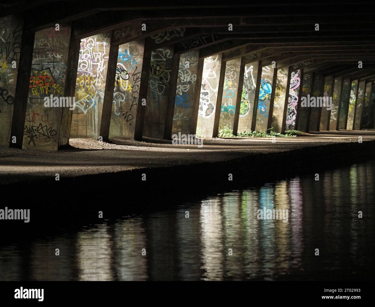 colourful graffiti on concrete arches of modern bridge over inland ...