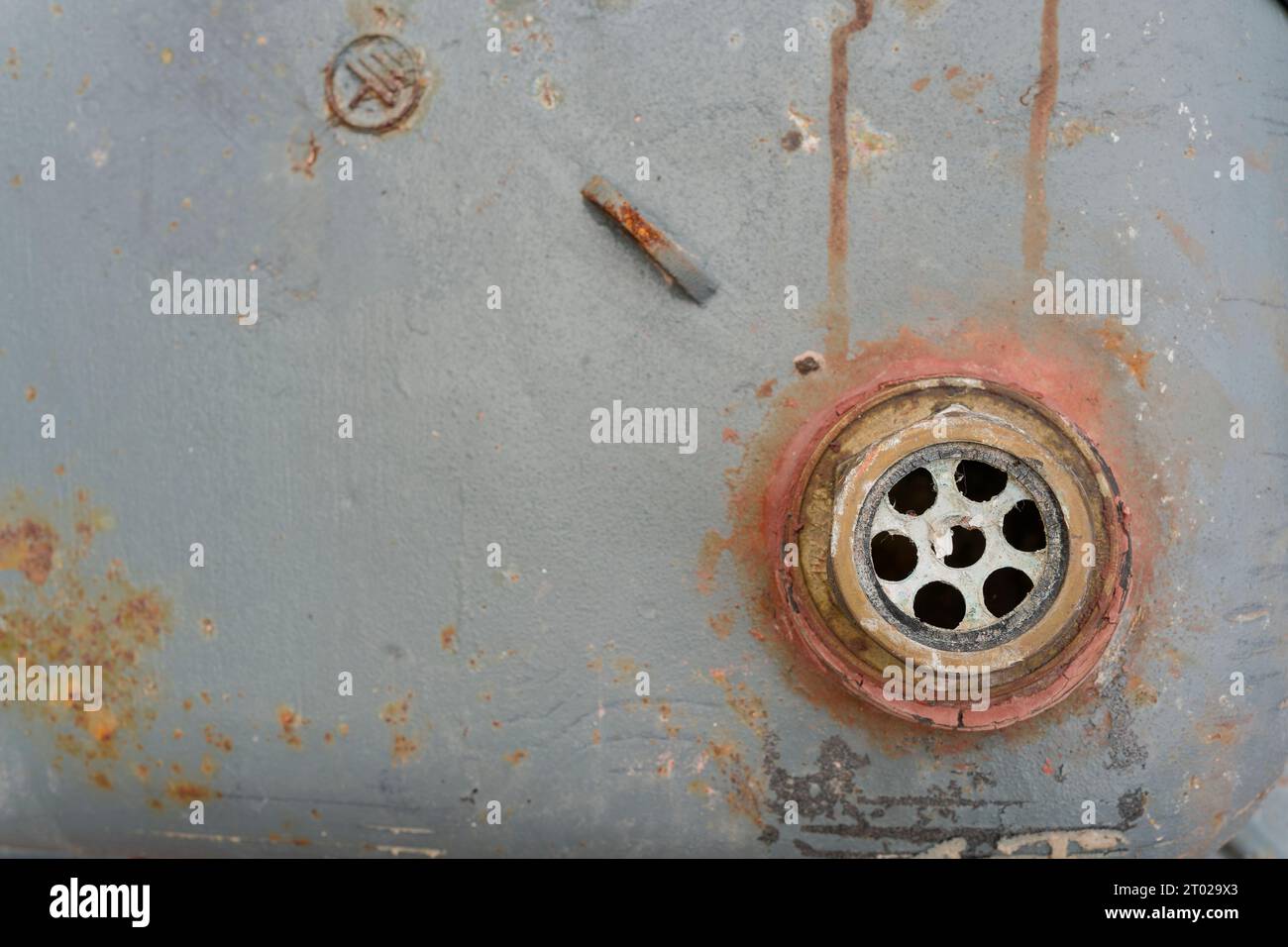 Underside of an old rusty metal sink with visible drain opening ...