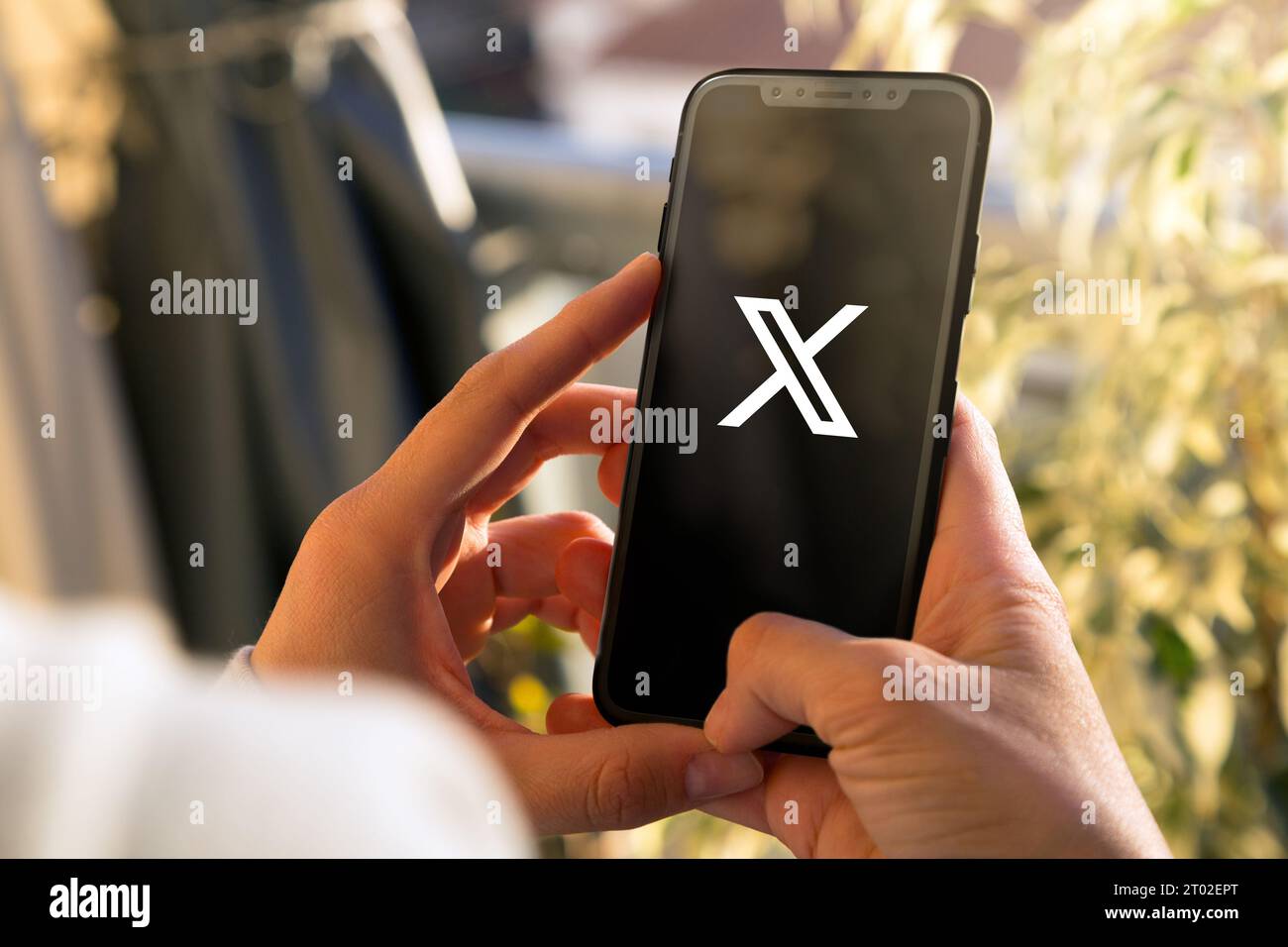 Woman holding her phone with the X social media logo on the screen ...