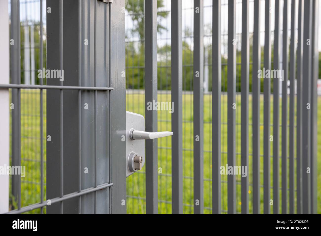 A close-up view of the white handle on the steel fence gate Stock Photo ...