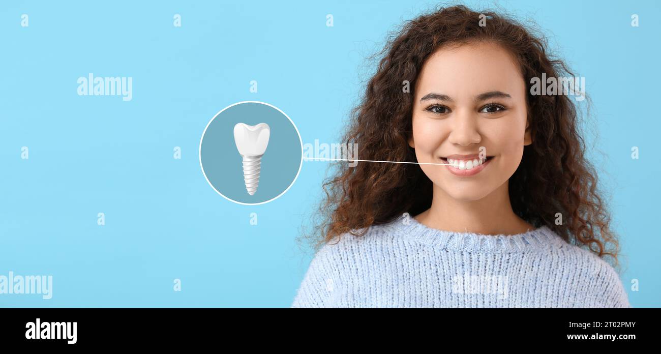 Beautiful young African-American woman with implanted tooth on light ...