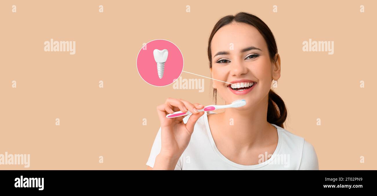 Young woman with dental implant brushing teeth on beige background ...
