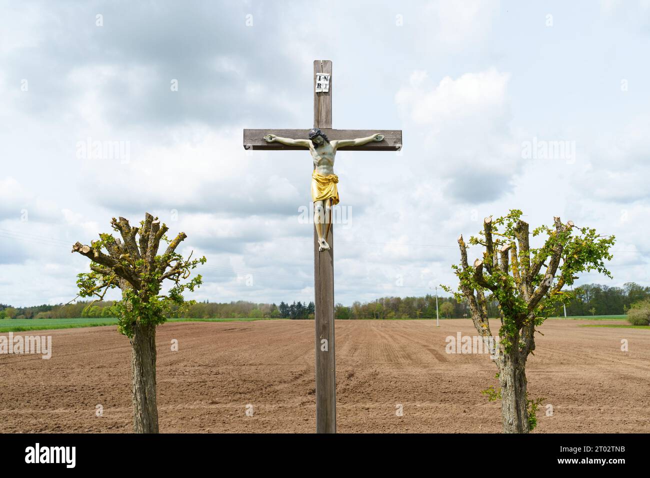 In front of a freshly plowed field stands the crucifixion of Jesus ...
