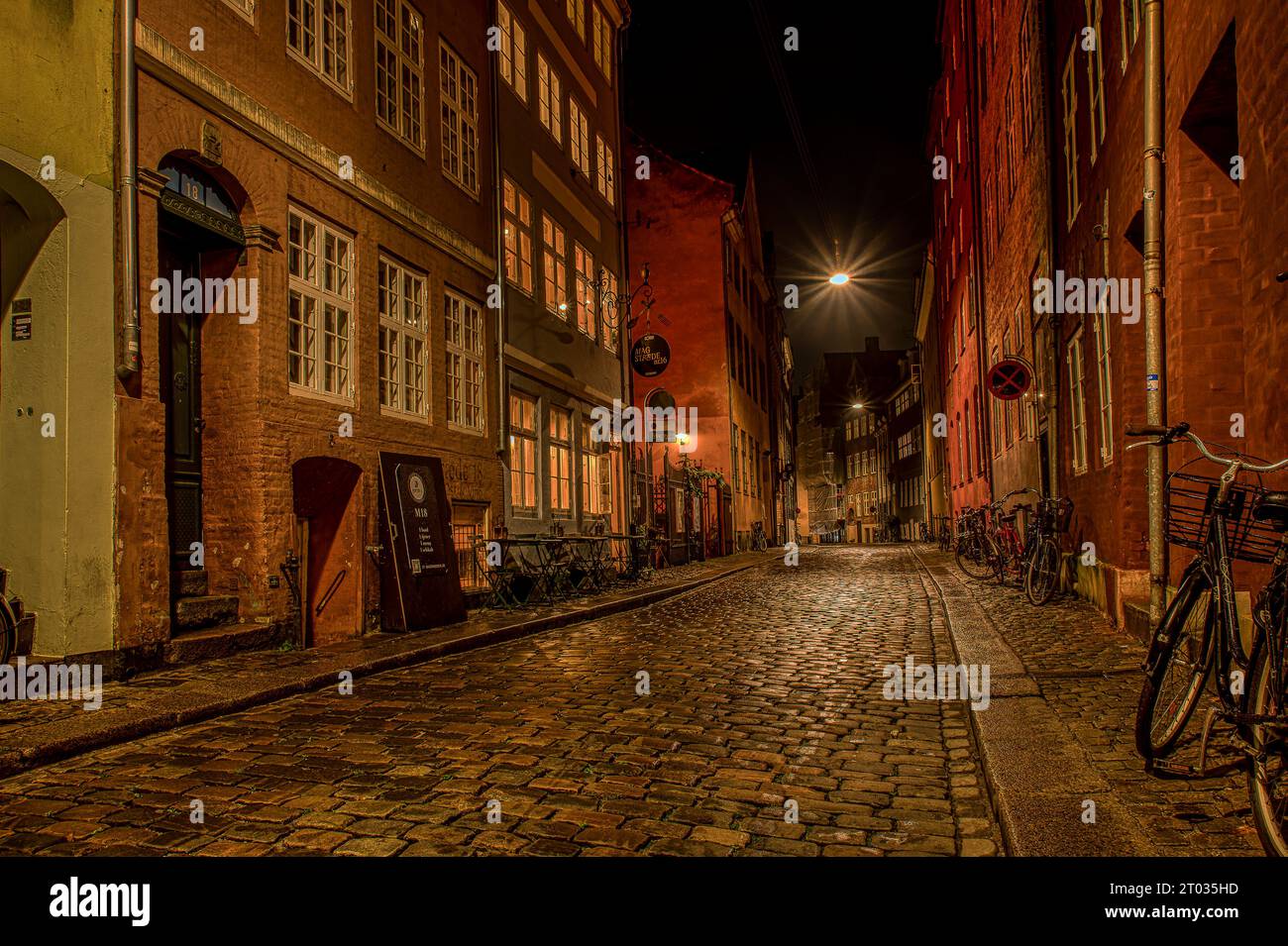 narrow alleyway at night with a streetlamp reflecting in the ...