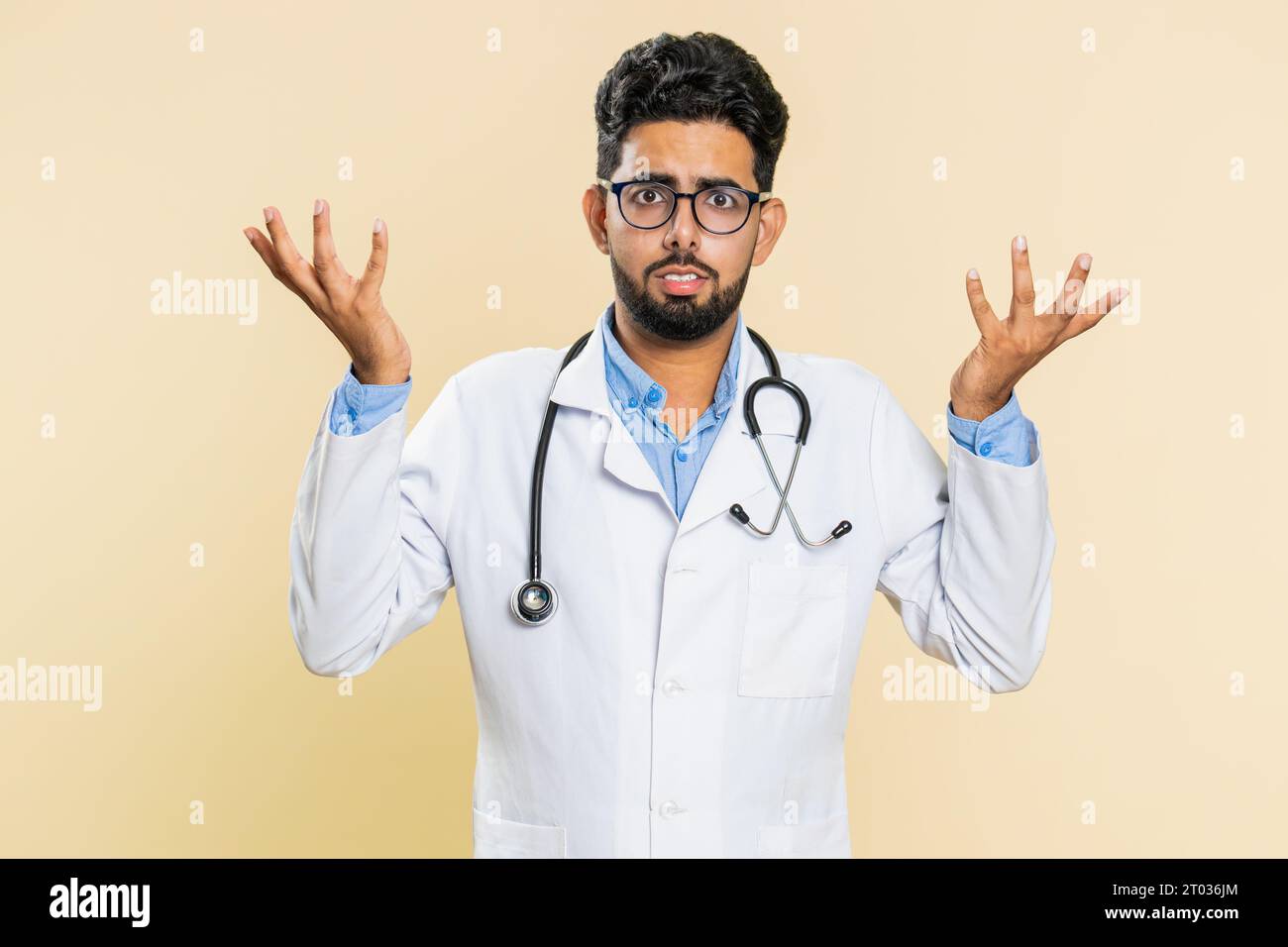 What. Why. Confused Indian doctor cardiologist man raising hands in ...