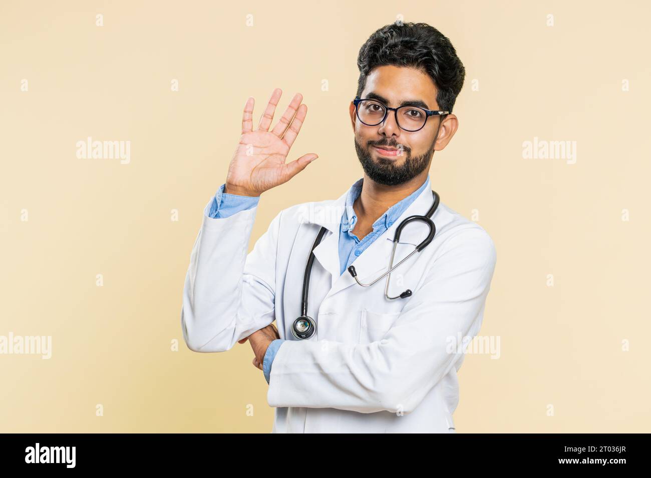 Indian smiling doctor cardiologist man waving hands gesturing hello ...