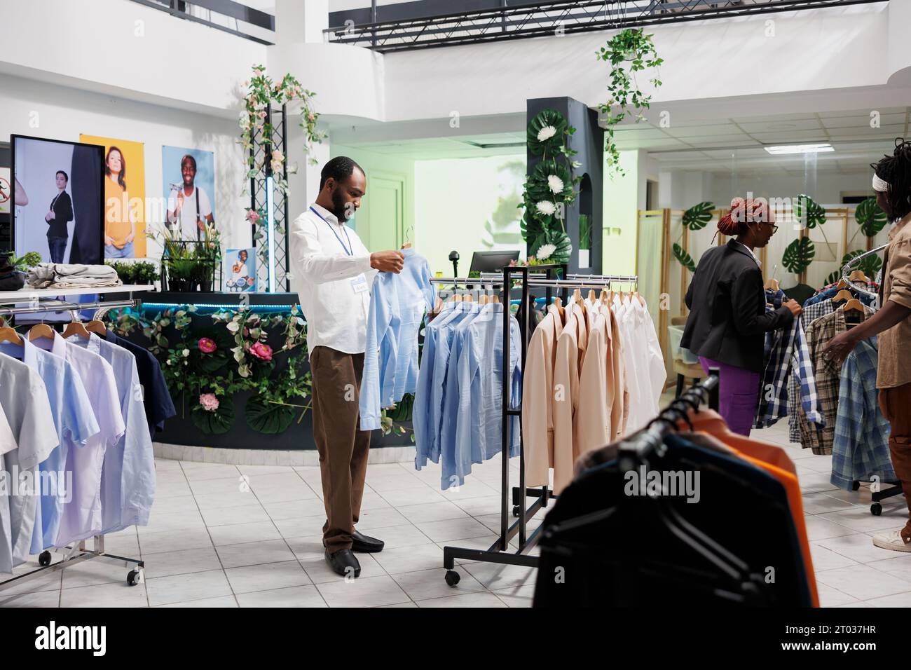 Clothes shop african american employee hanging shirt on rack. Fashion ...