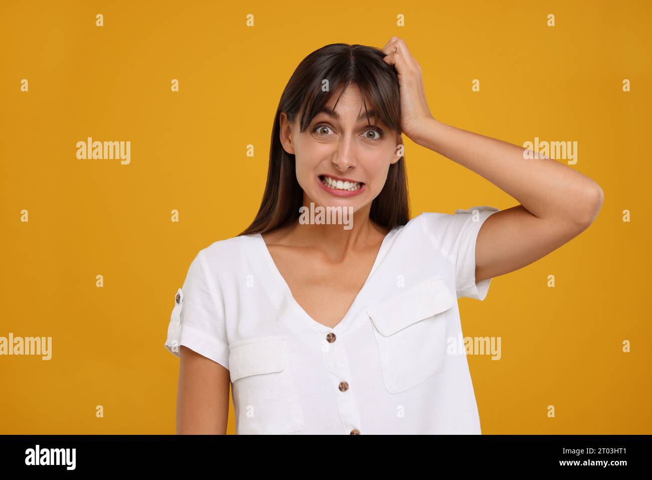 Embarrassed woman scratching head on orange background Stock Photo - Alamy