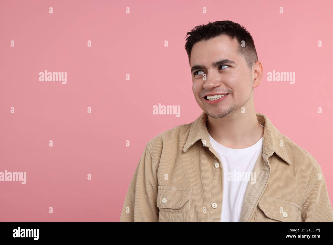 Portrait of embarrassed young man on pink background, space for text ...