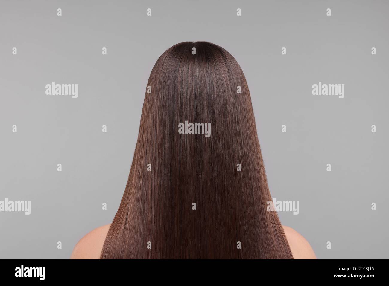 Woman with smooth healthy hair after treatment on light grey background ...