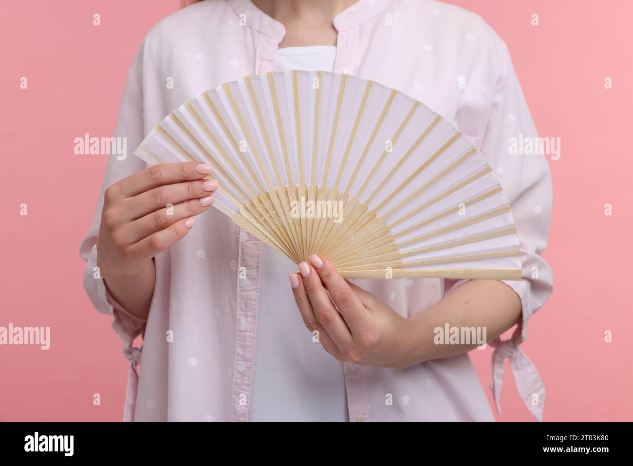 Woman with hand fan on pink background, closeup Stock Photo - Alamy