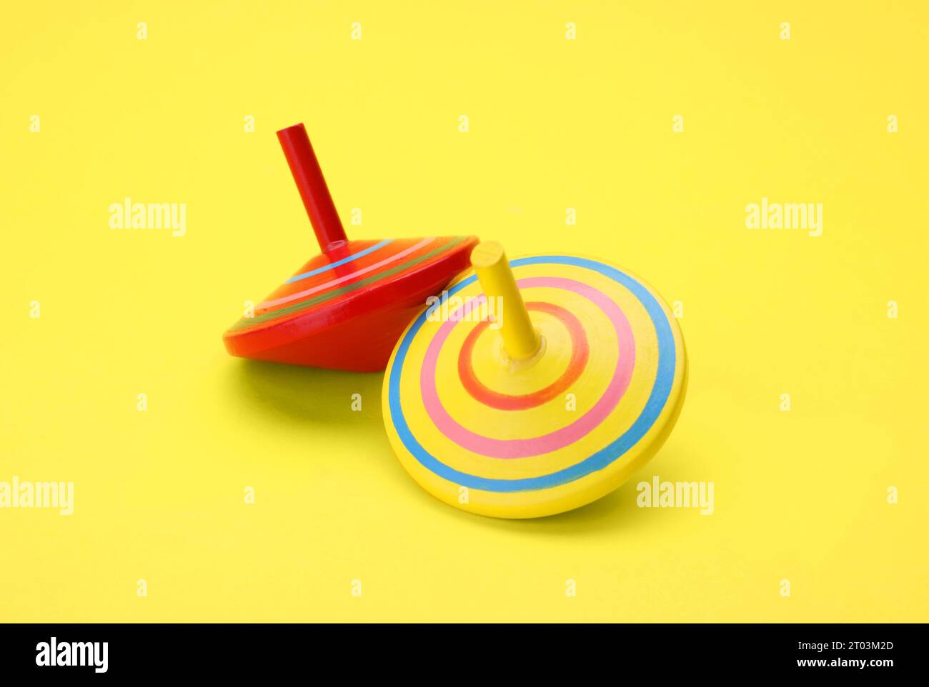 Two bright spinning top on yellow background. Toy whirligig Stock Photo ...