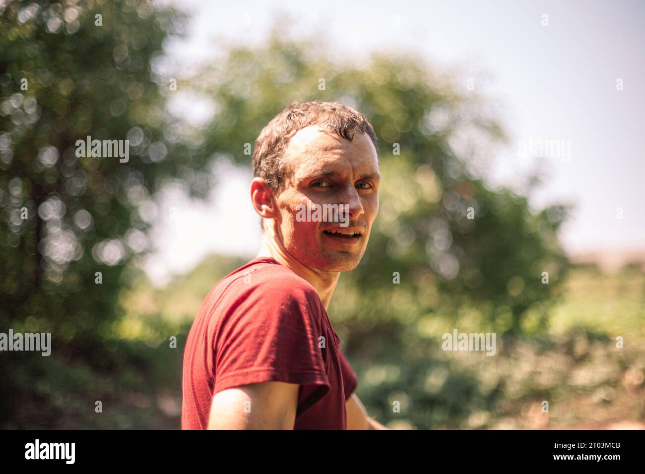 Portrait of tired man standing in the garden during summer heat ...