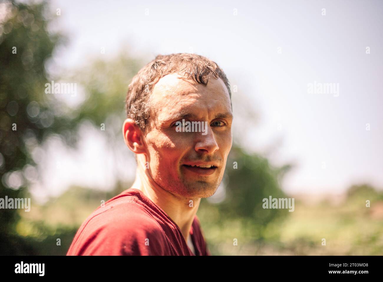 Portrait of happy tired man standing in the garden during summer heat ...