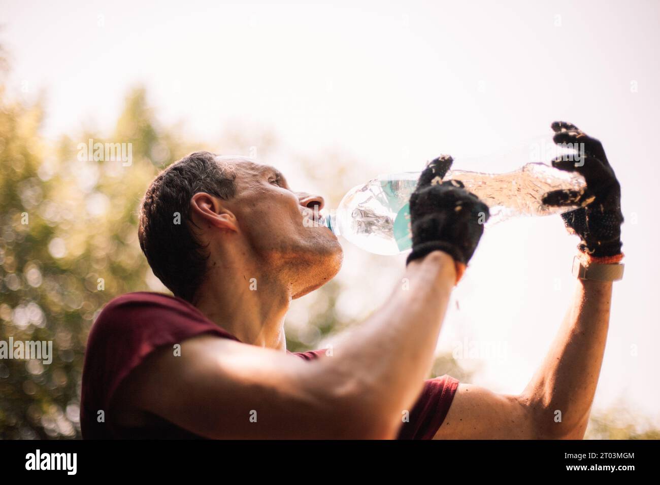 Thirsty man farmer drinking water from bottle in the garden during ...