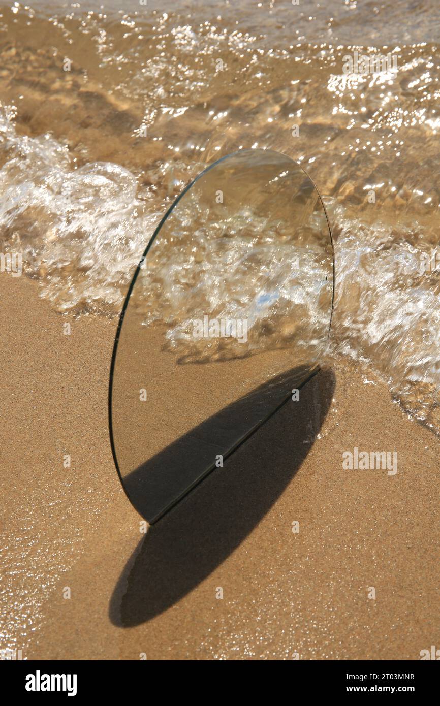 Round mirror reflecting sea on sandy beach Stock Photo - Alamy