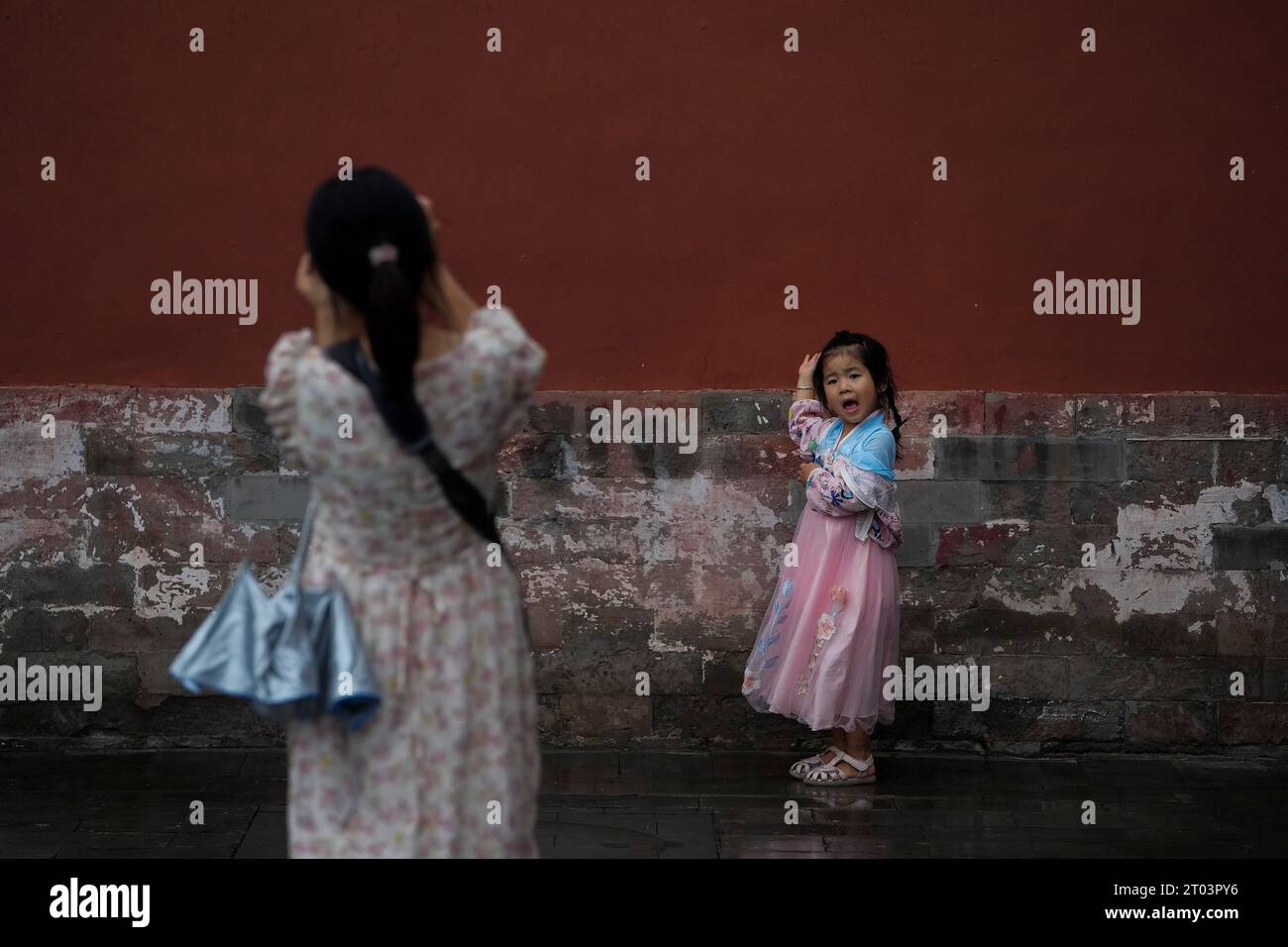 A child wearing a traditional costume poses for a photo against a wall ...