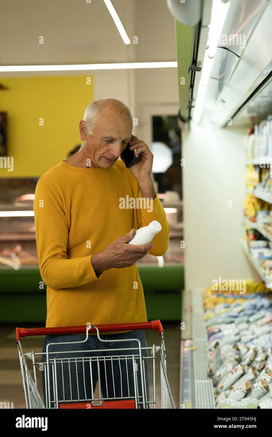 Old man choosing products on grocery shopping buying food in ...