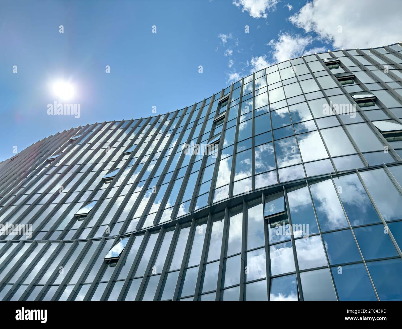 modern office building exterior. windows reflect the blue sky with ...