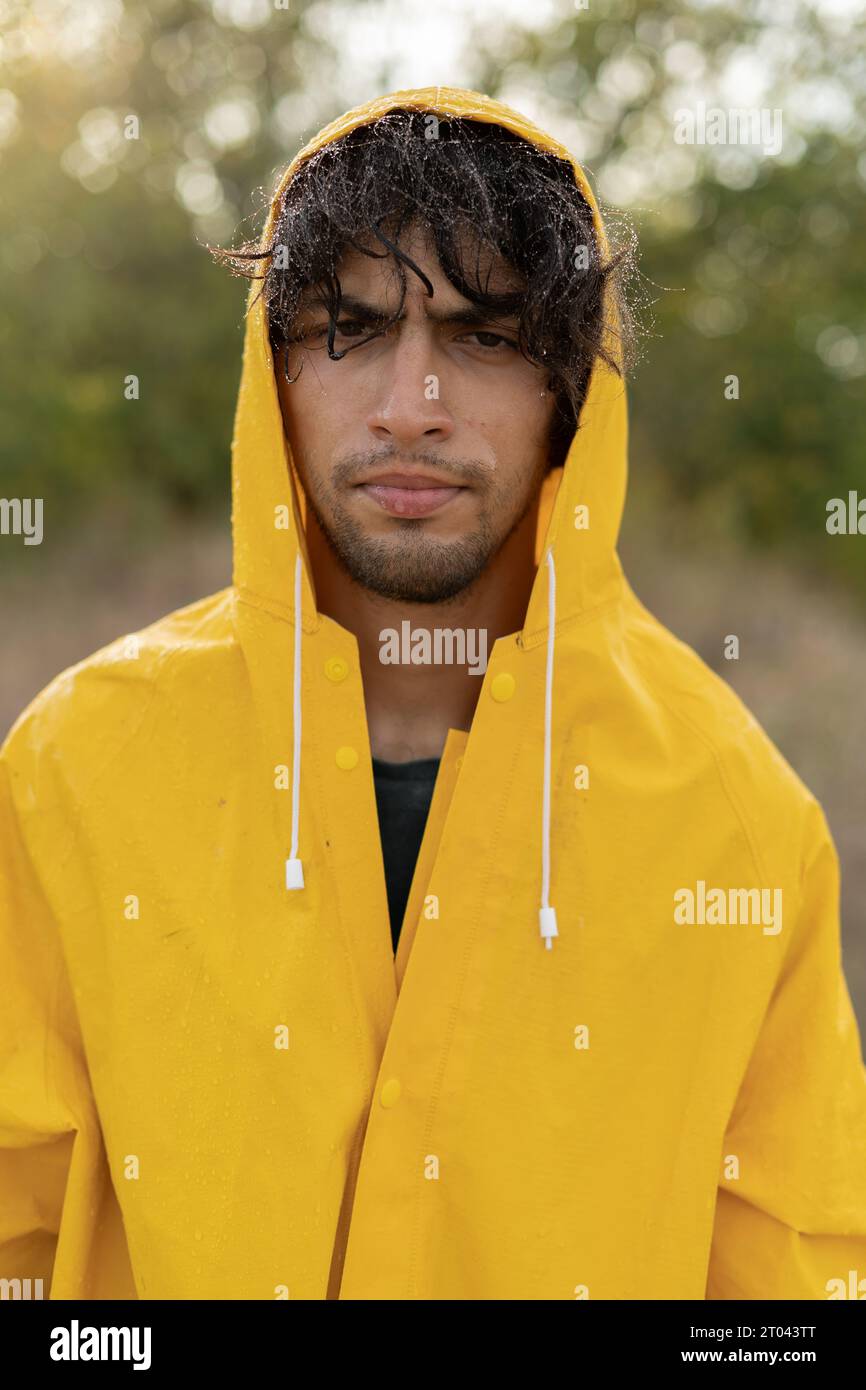 Portrait of an Arab guy in a yellow raincoat getting wet in the rain ...