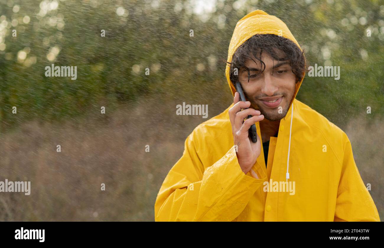 Arabic man holding umbrella out in the rain talking on a mobile phone ...