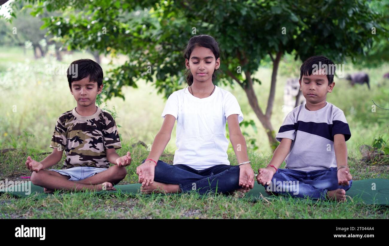 Happy small children sitting in lotus position on comfortable mat with ...
