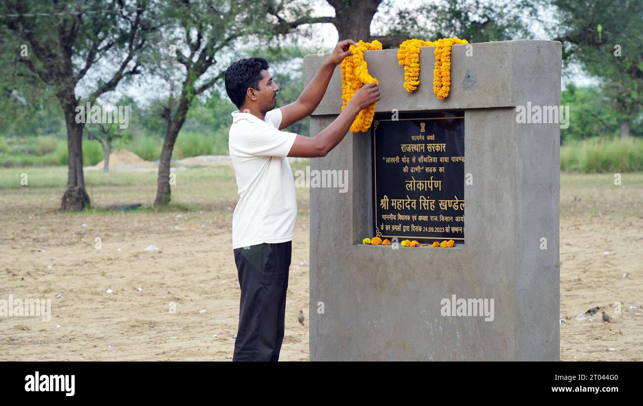 An India Young man standing on Newly made Road Inauguration board with ...