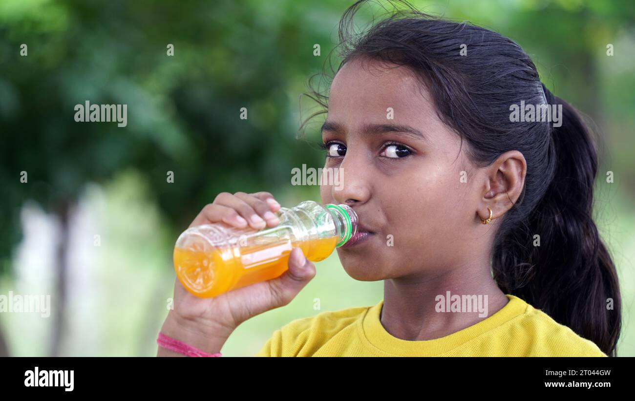 Girl drinking juice. Asian kid drinking from plastic bottle. Portrait ...