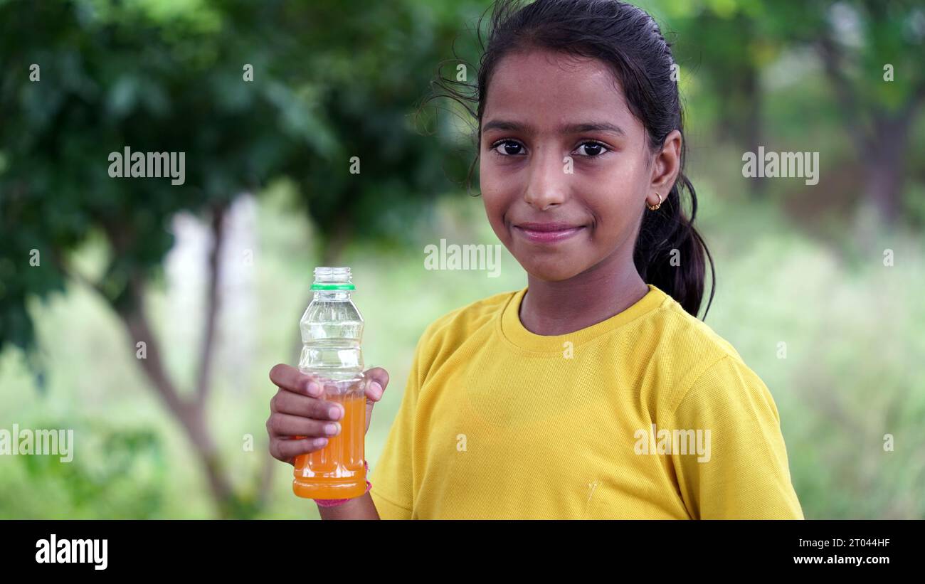 Girl drinking juice. Asian kid drinking from plastic bottle. Portrait of a girl drinking orange ...