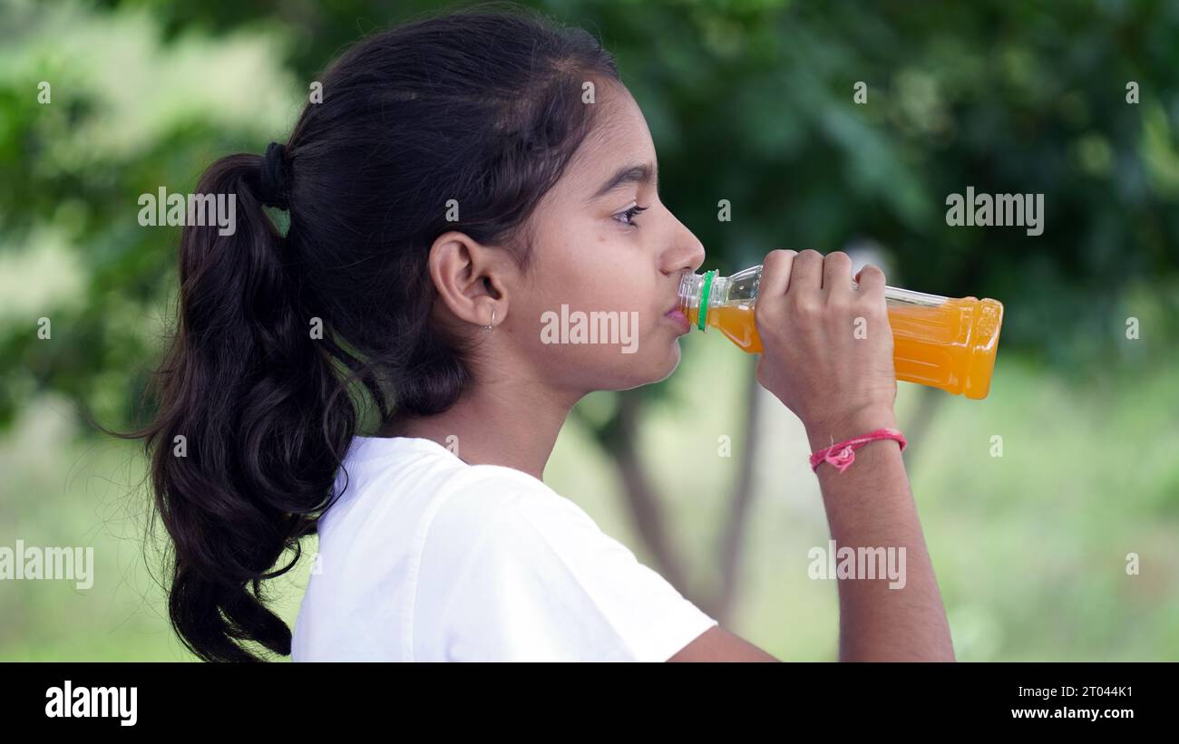 Girl drinking juice. Asian kid drinking from plastic bottle. Portrait ...
